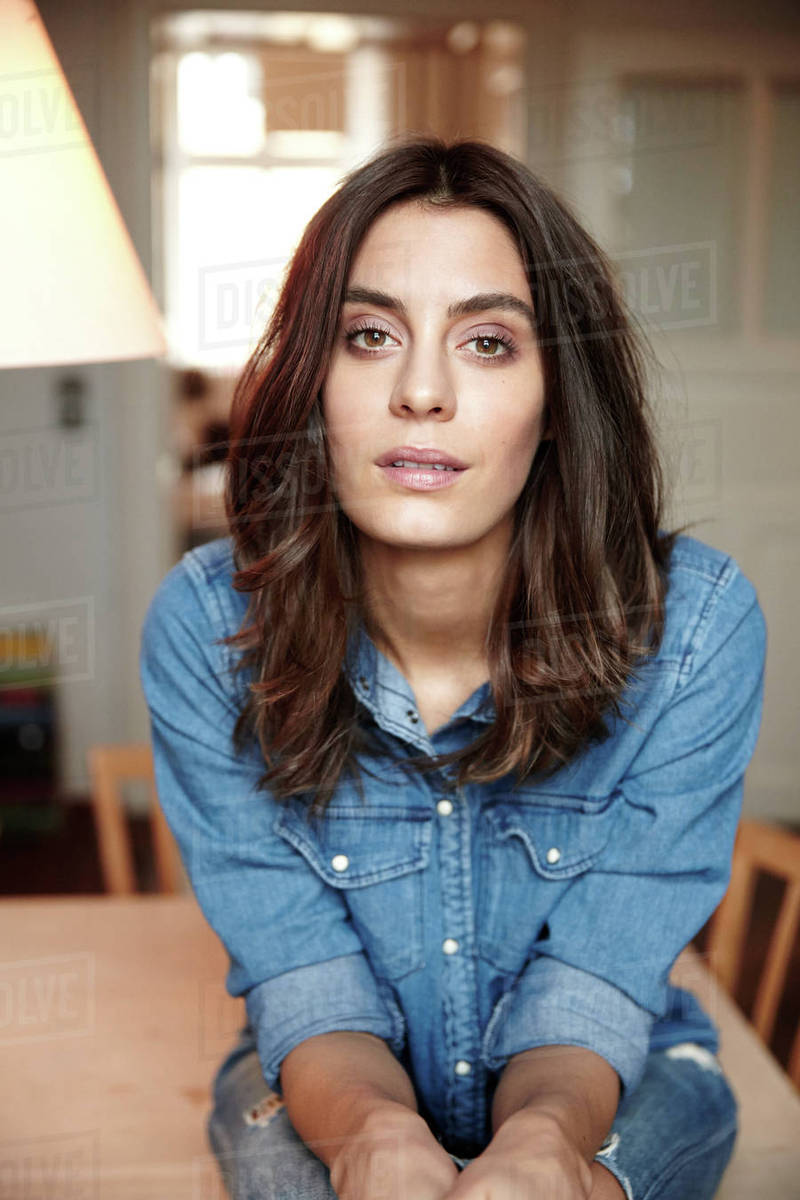 Portrait of sultry young woman sitting on dining table - Royalty-free ...