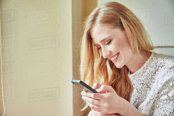Young woman reading smartphone text at home - Royalty-free Stock Photo ...