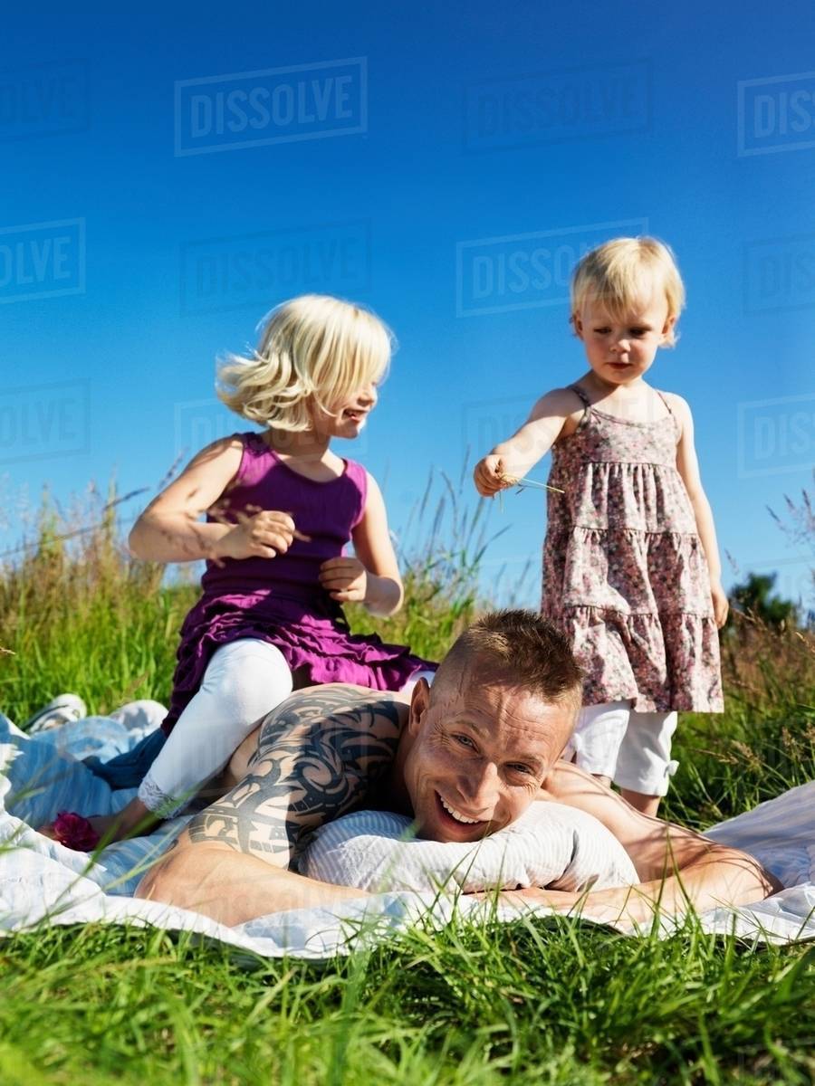 Children playing with father outdoors - Stock Photo - Dissolve