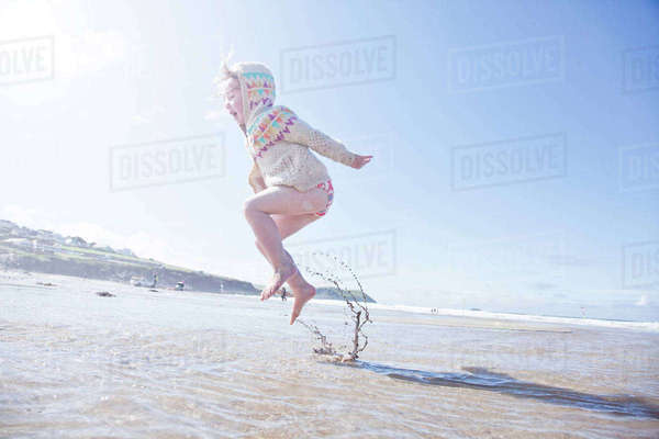 Girl jumping in water, Polzeath Beach, Cornwall - Royalty-free Stock ...