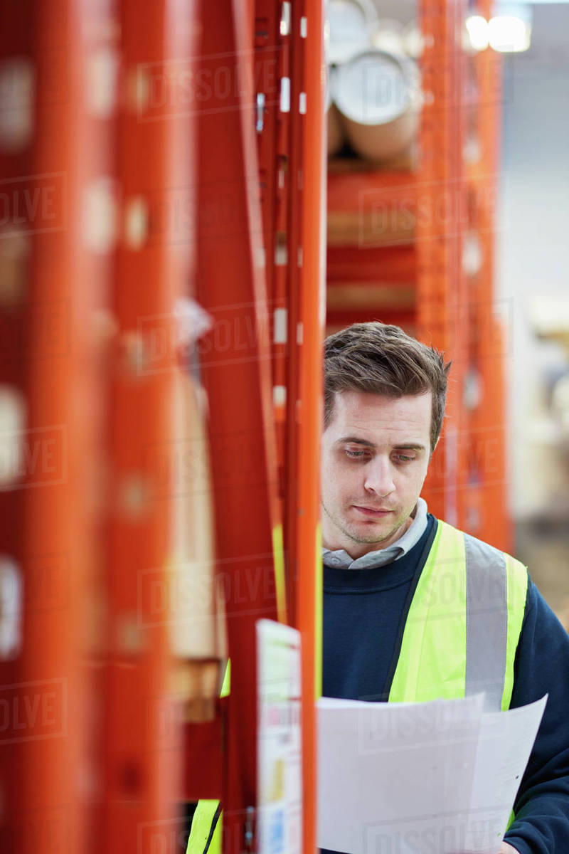 Male factory worker checking paperwork in factory warehouse - Royalty ...