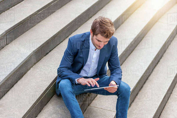 Man sitting on steps looking down using digital tablet - Stock Photo ...