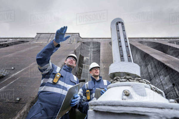 Workers at foot of dam at hydroelectric power station - Stock Photo ...