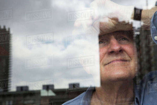 Man smiling and leaning head against window - Stock Photo - Dissolve