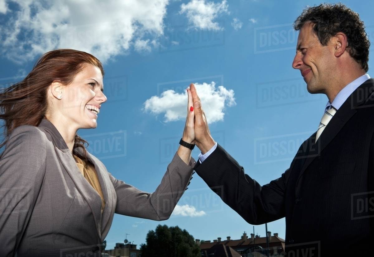 Business people high fiving outdoors - Stock Photo - Dissolve