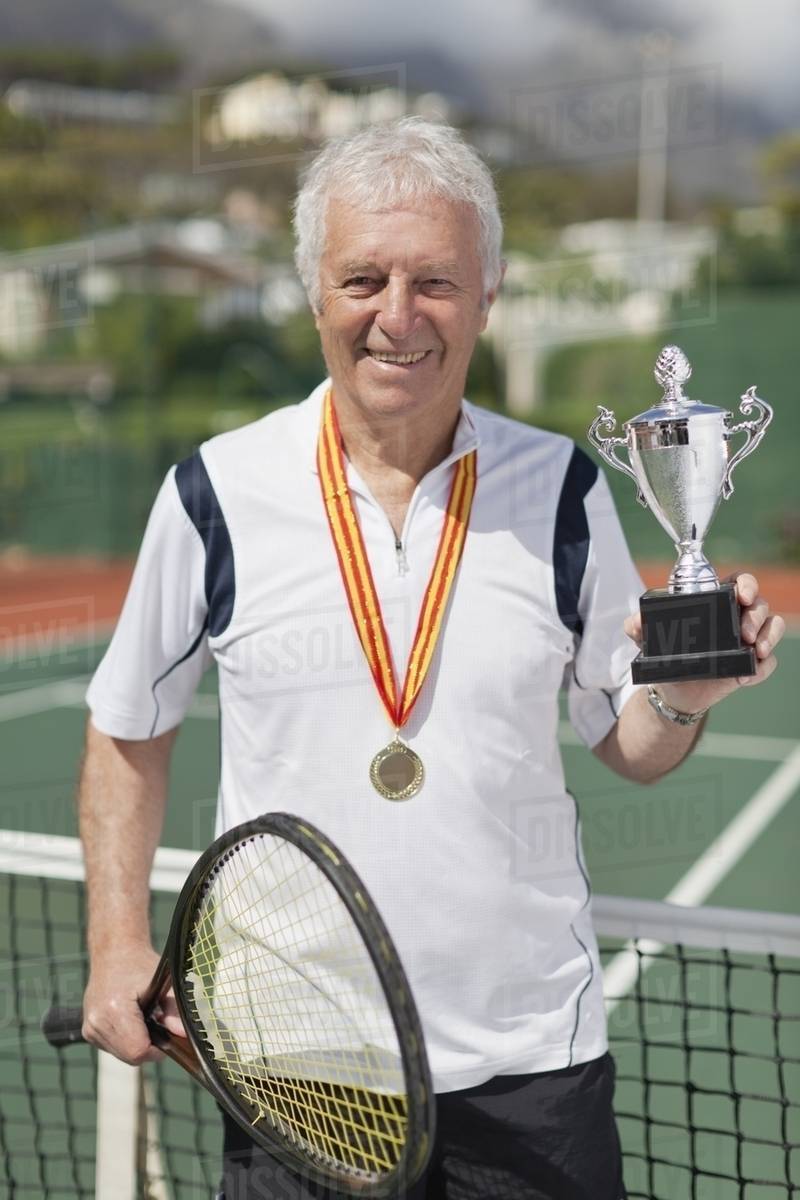Older man with trophy on tennis court - Stock Photo - Dissolve