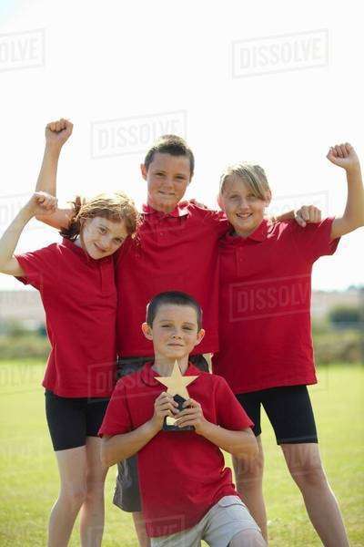 Children cheering with trophy outdoors - Stock Photo - Dissolve