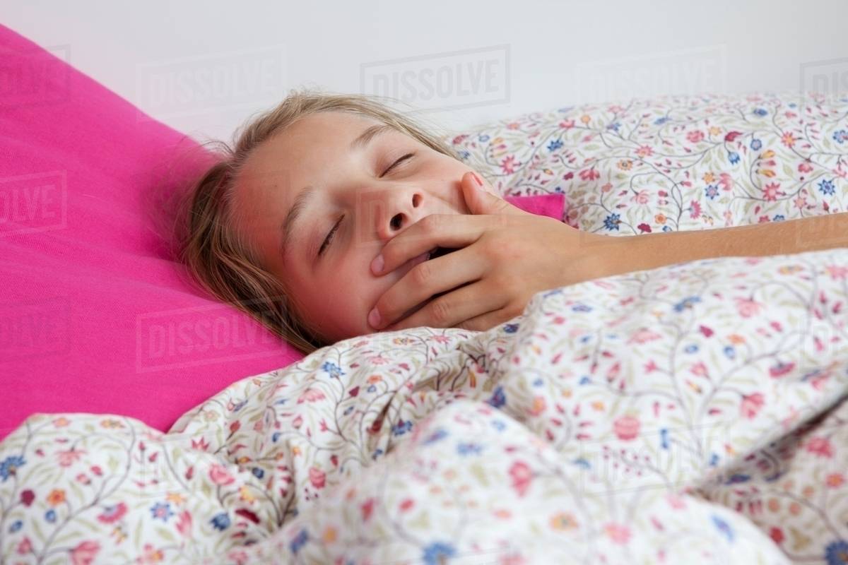 Close up of girl yawning in bed - Stock Photo - Dissolve