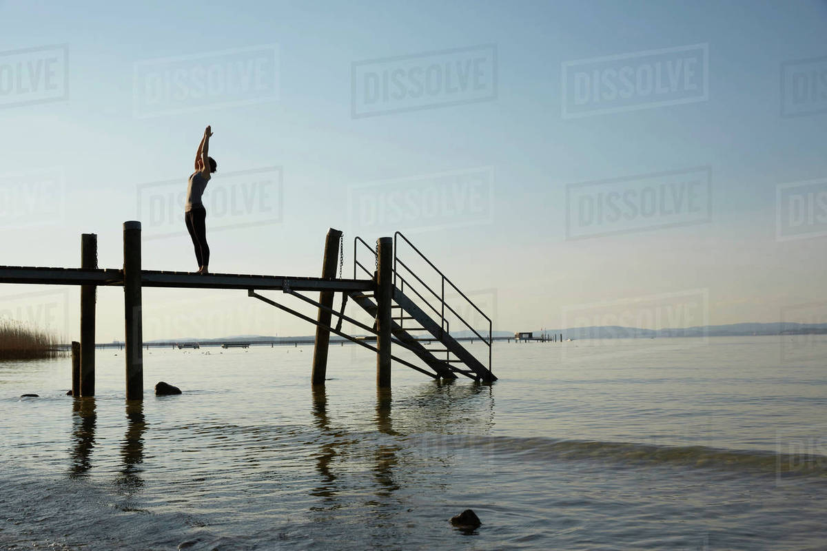 Silhouette of woman on pier arms raised in yoga position - Stock Photo ...