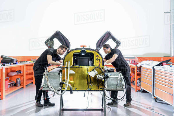 Engineers with car under construction in racing car factory - Stock ...