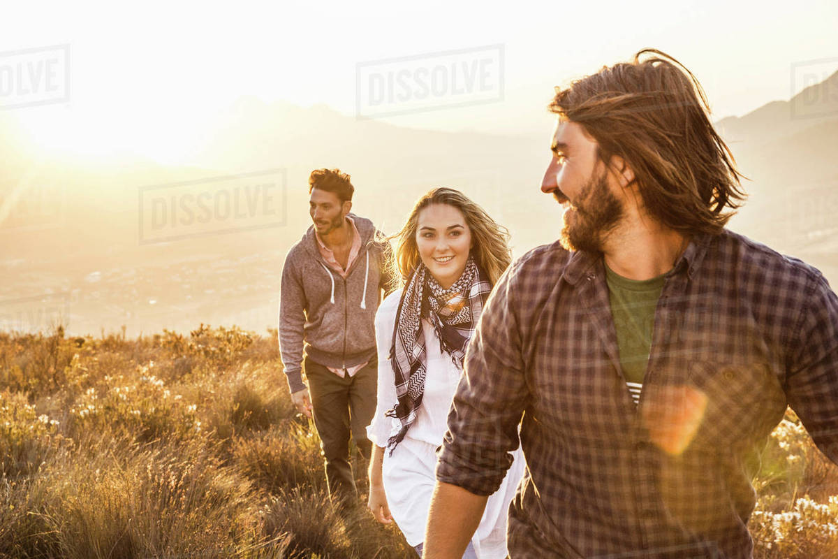 Friends rambling on grassland smiling - Stock Photo - Dissolve
