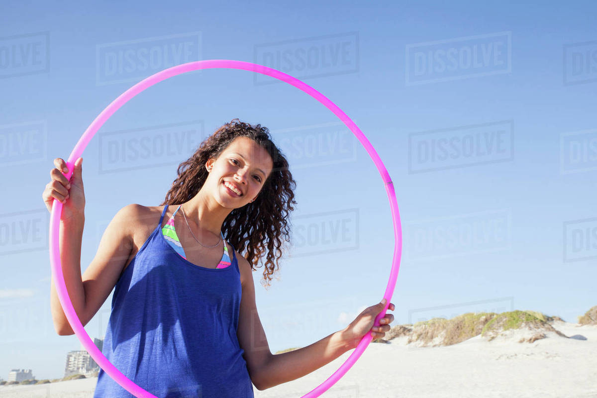 Woman on beach looking through hula hoop at camera smiling - Royalty ...