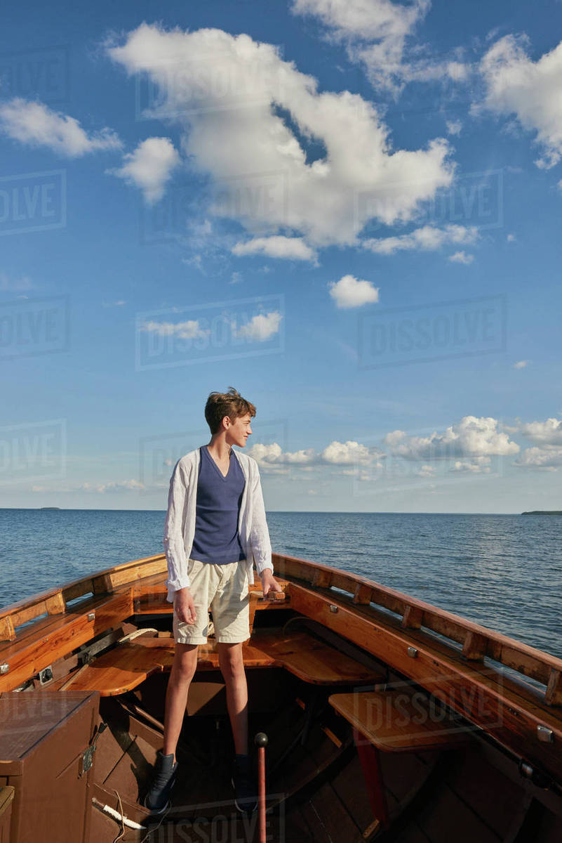 Teenage boy standing on boat looking away - Stock Photo - Dissolve