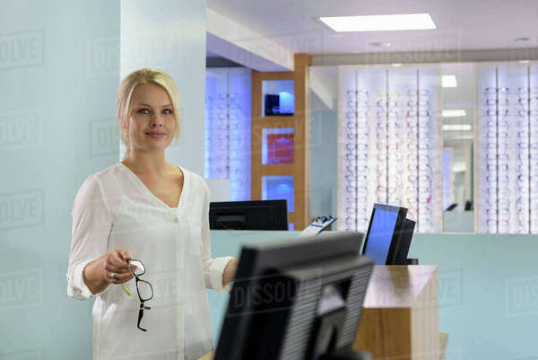 Portrait of receptionist at desk welcoming patients at small business ...