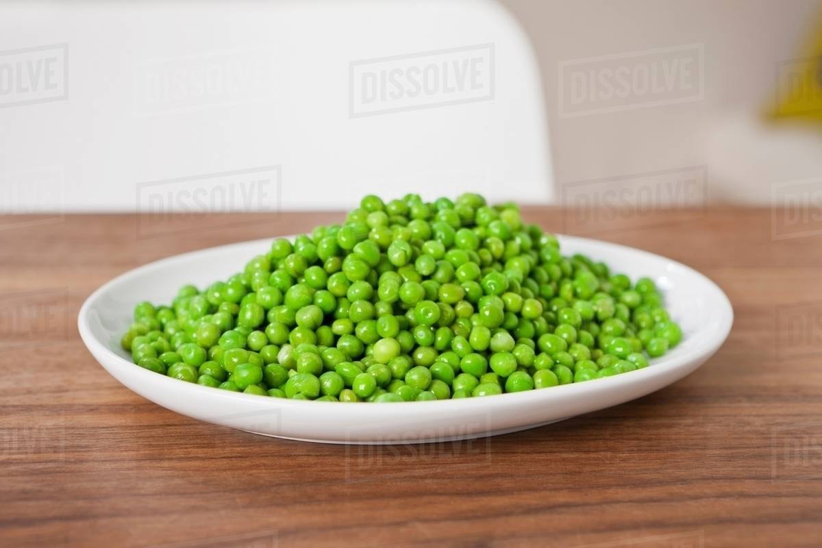 Close up of plate of peas on table - Stock Photo - Dissolve