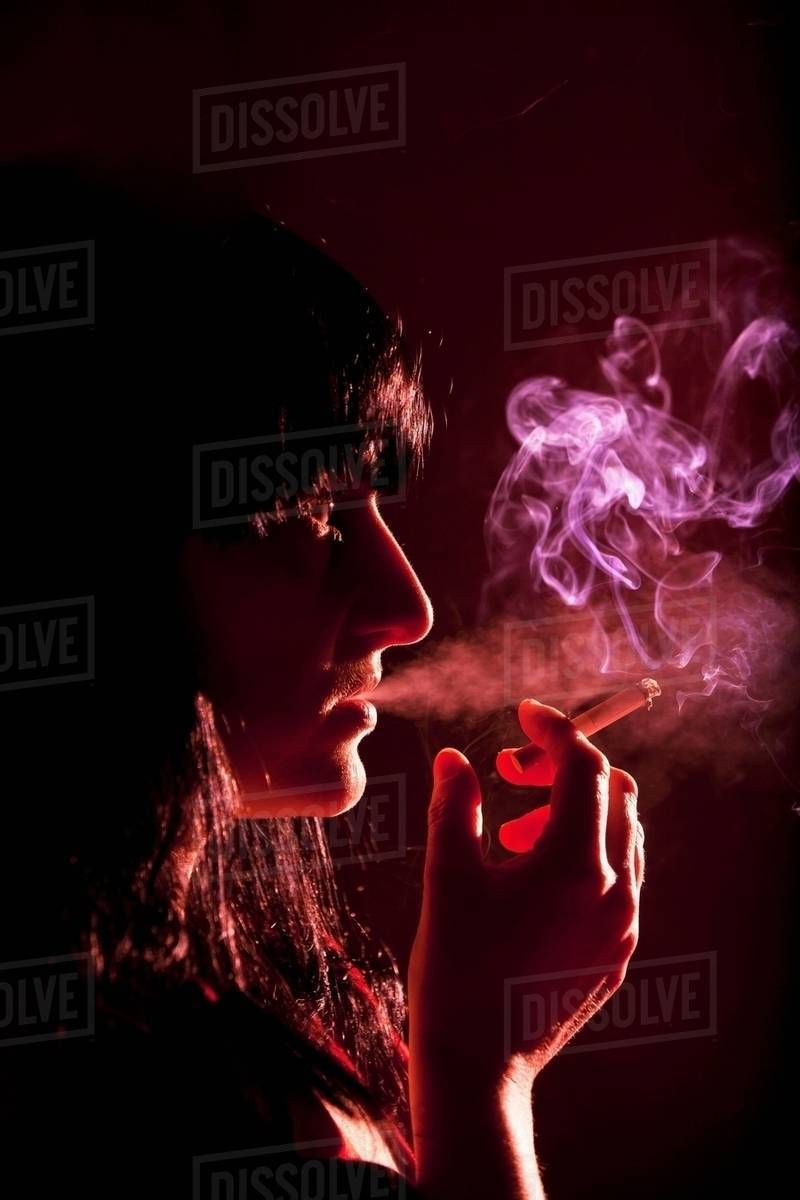Illuminated profile of woman smoking - Stock Photo - Dissolve