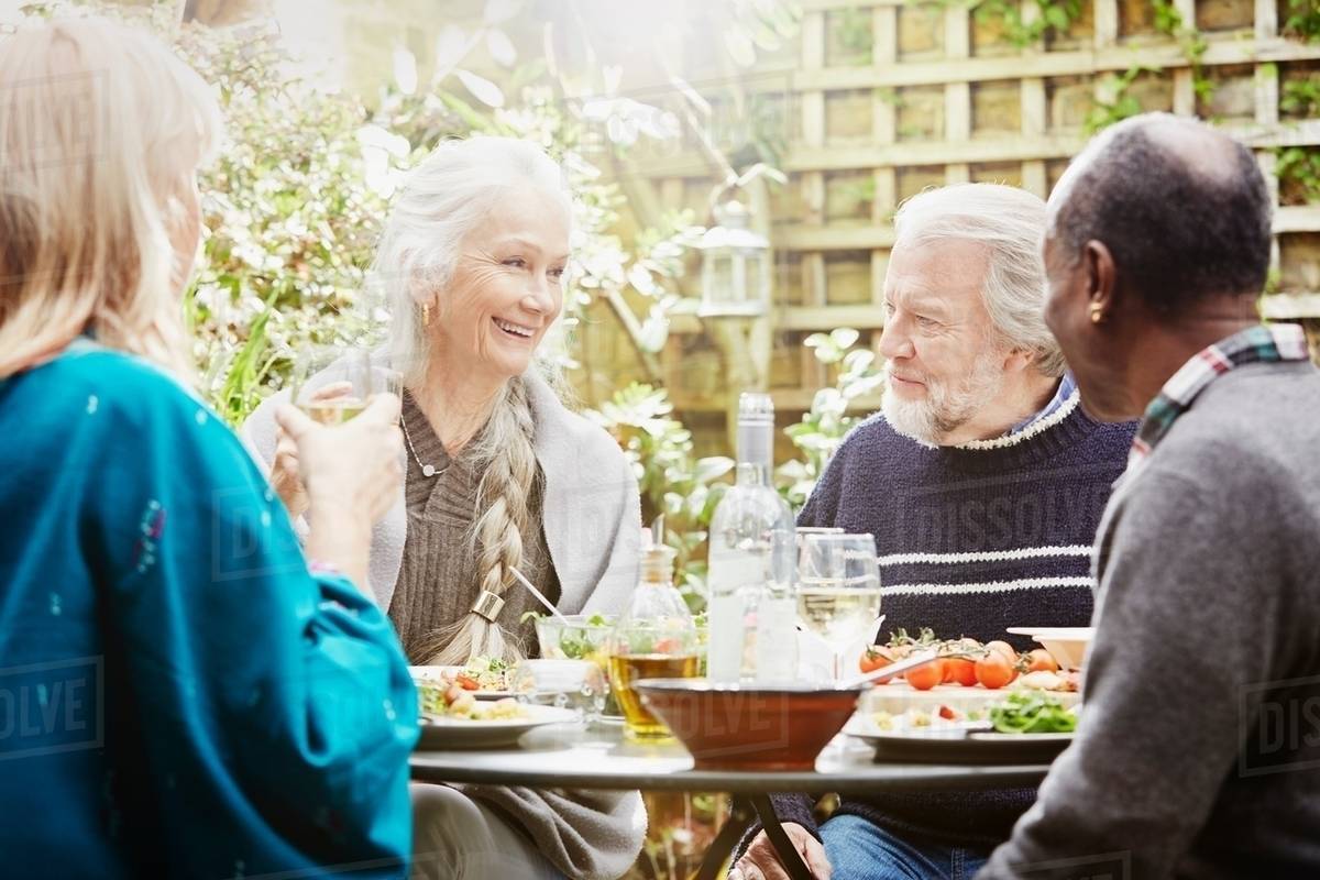 Senior friends eating meal in garden - Royalty-free Stock Photo | Dissolve
