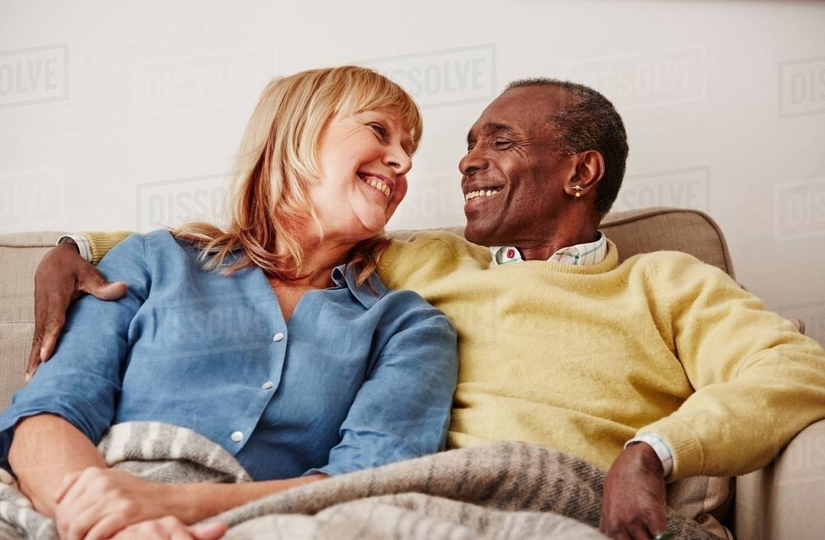 Couple sitting on sofa, smiling - Royalty-free Stock Photo | Dissolve