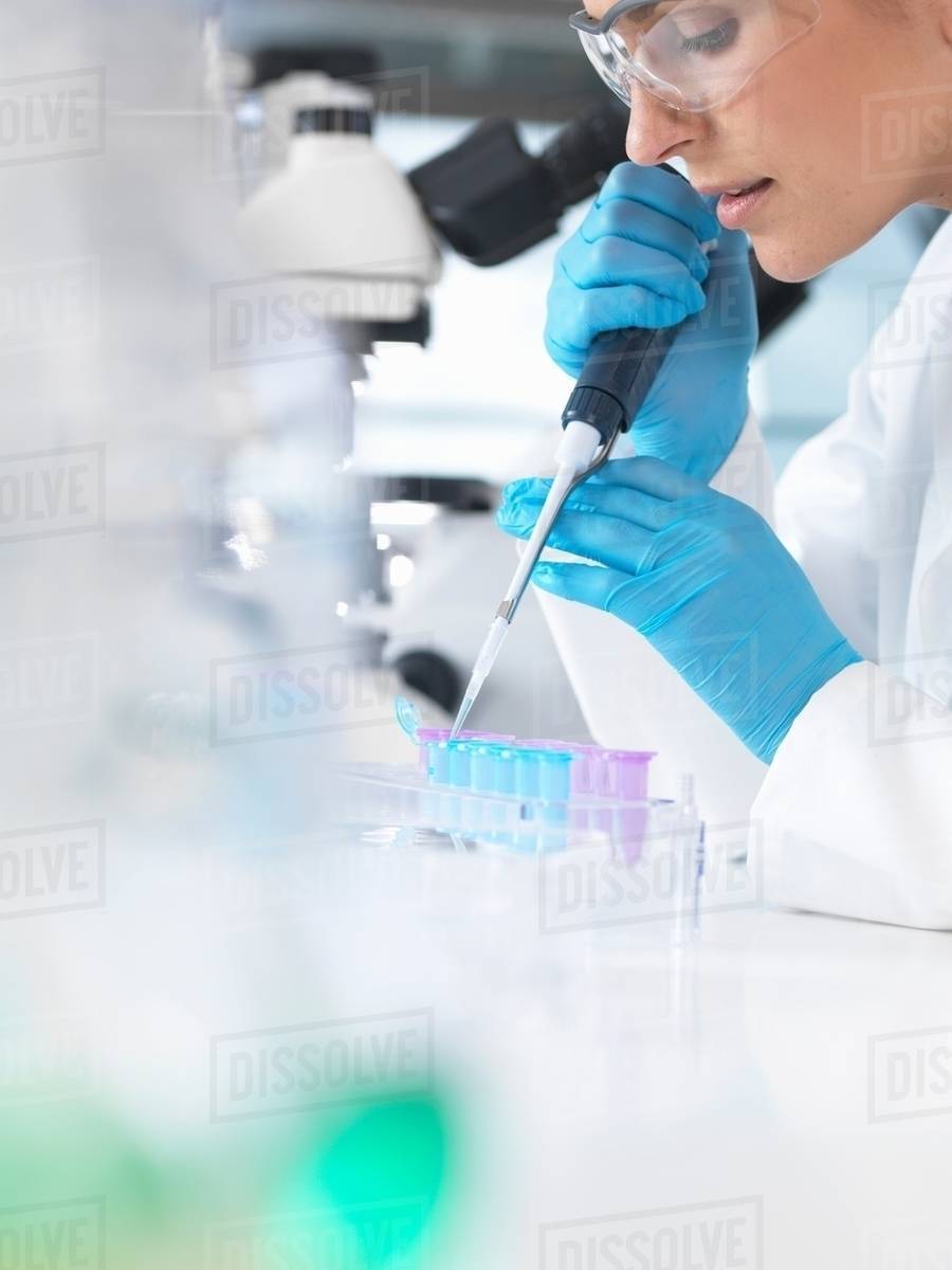Female scientist pipetting sample into a vial for analytical testing in ...