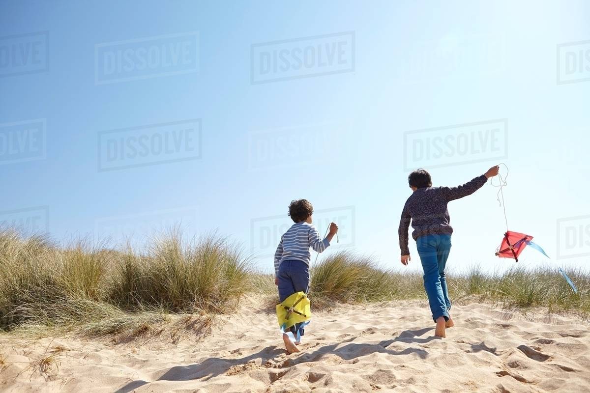 Two young boys, flying kites on beach - Stock Photo - Dissolve