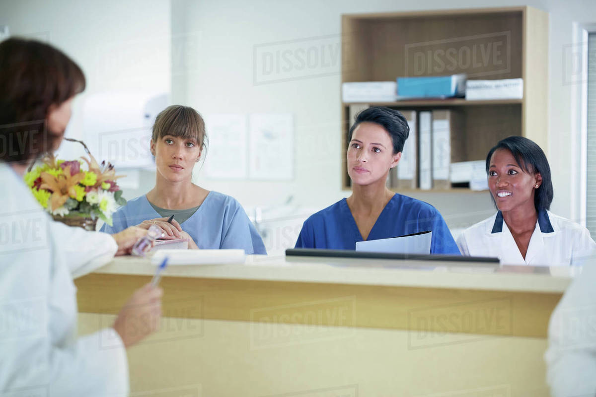 Female doctor having discussion with nurses at nurses station in ...