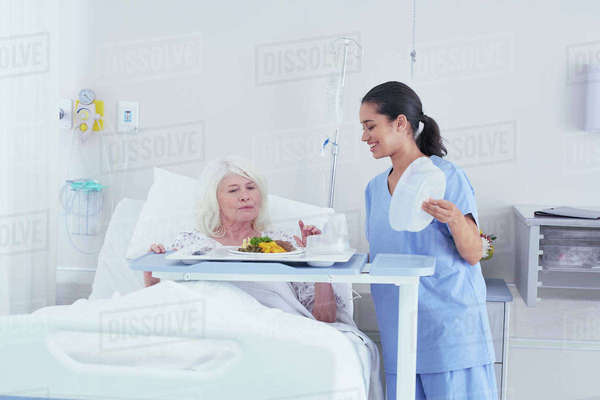 Nurse serving lunch to senior female patient in hospital bed - Royalty ...