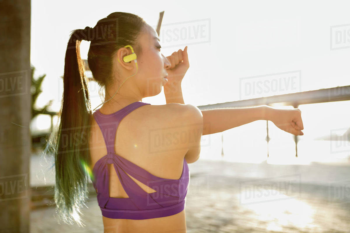 Rear view of woman wearing crop top stretching arm - Royalty-free Stock ...