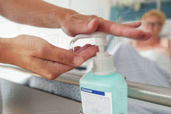Nurse using hand sanitiser on hospital bed - Royalty-free Stock Photo ...