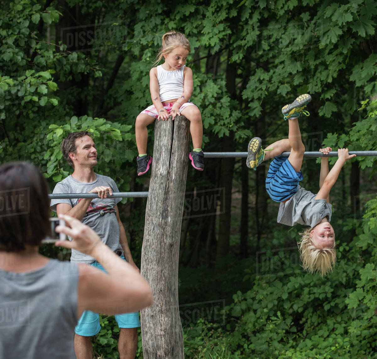 Mother photographing children playing on monkey bar - Royalty-free ...