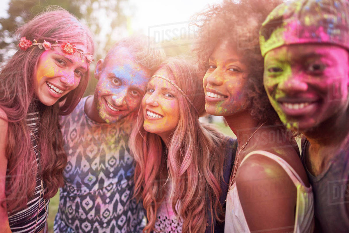 Portrait of group of friends at festival, covered in colourful powder ...