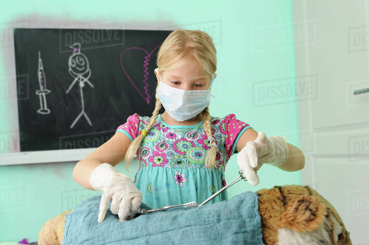 Girl pretending to be vet operating on toy tiger - Royalty-free Stock ...