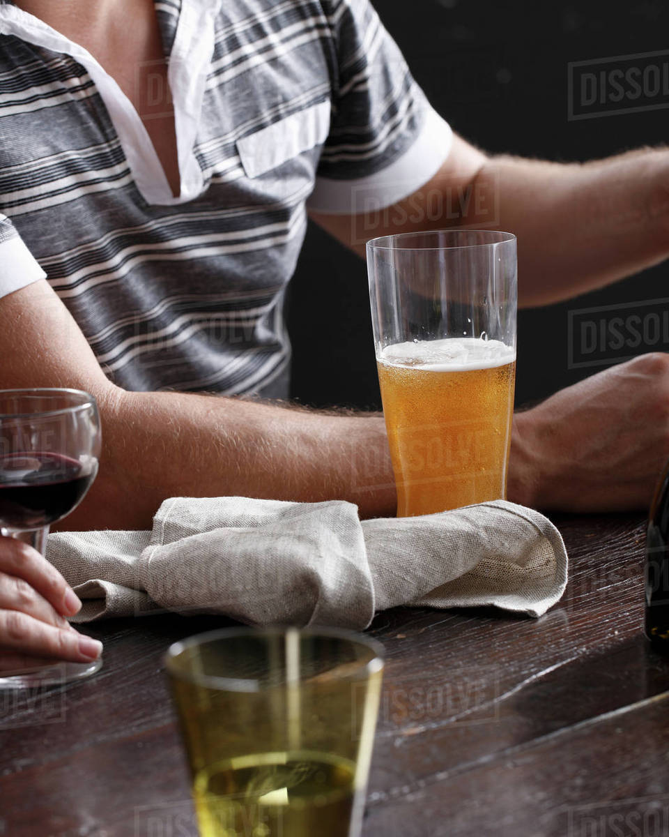 Two people drinking drinks in restaurant, mid section, close-up ...