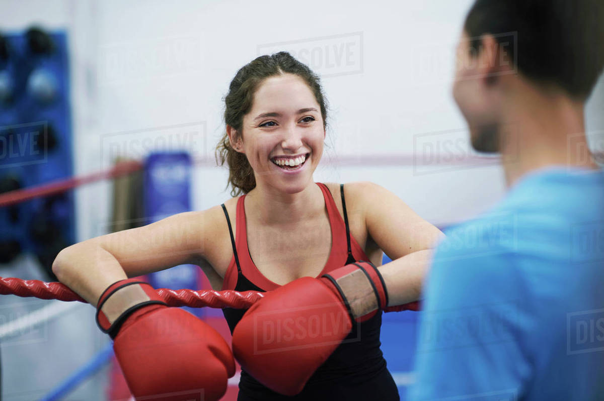 Young female boxer leaning on boxing ring ropes chatting - Stock Photo ...