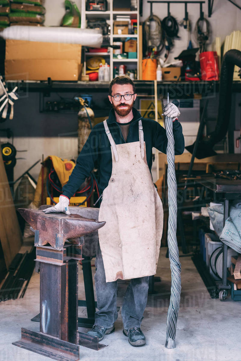Portrait of metalworker leaning on anvil in forge workshop - Stock ...