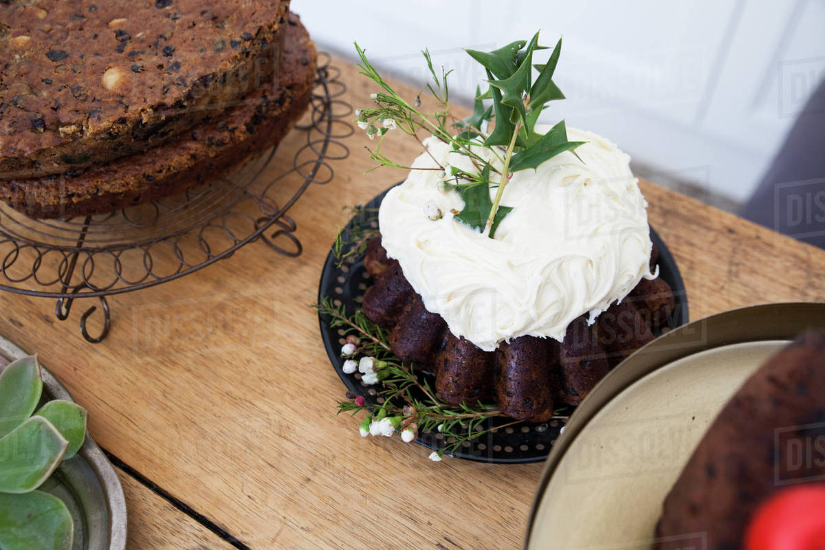 Cakes on kitchen counter, one decorated with icing and leaves - Stock ...