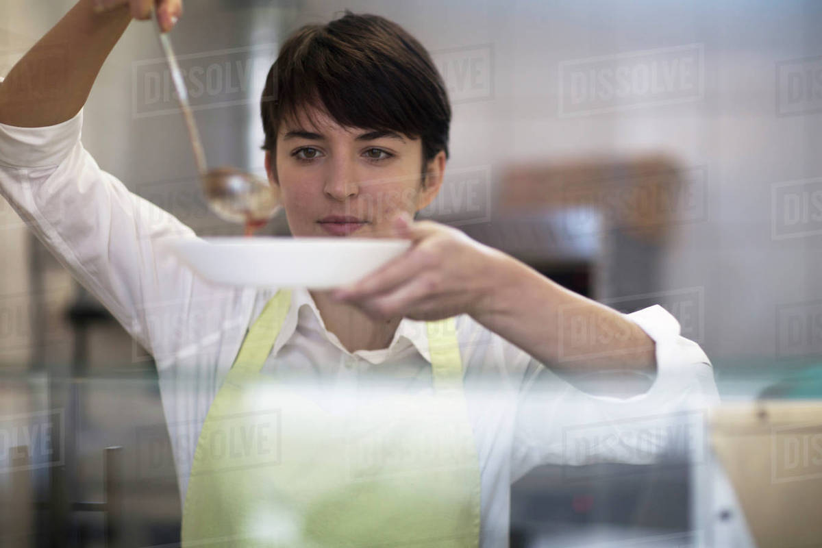 Young woman spooning food into bowl in fast food shop - Royalty-free ...