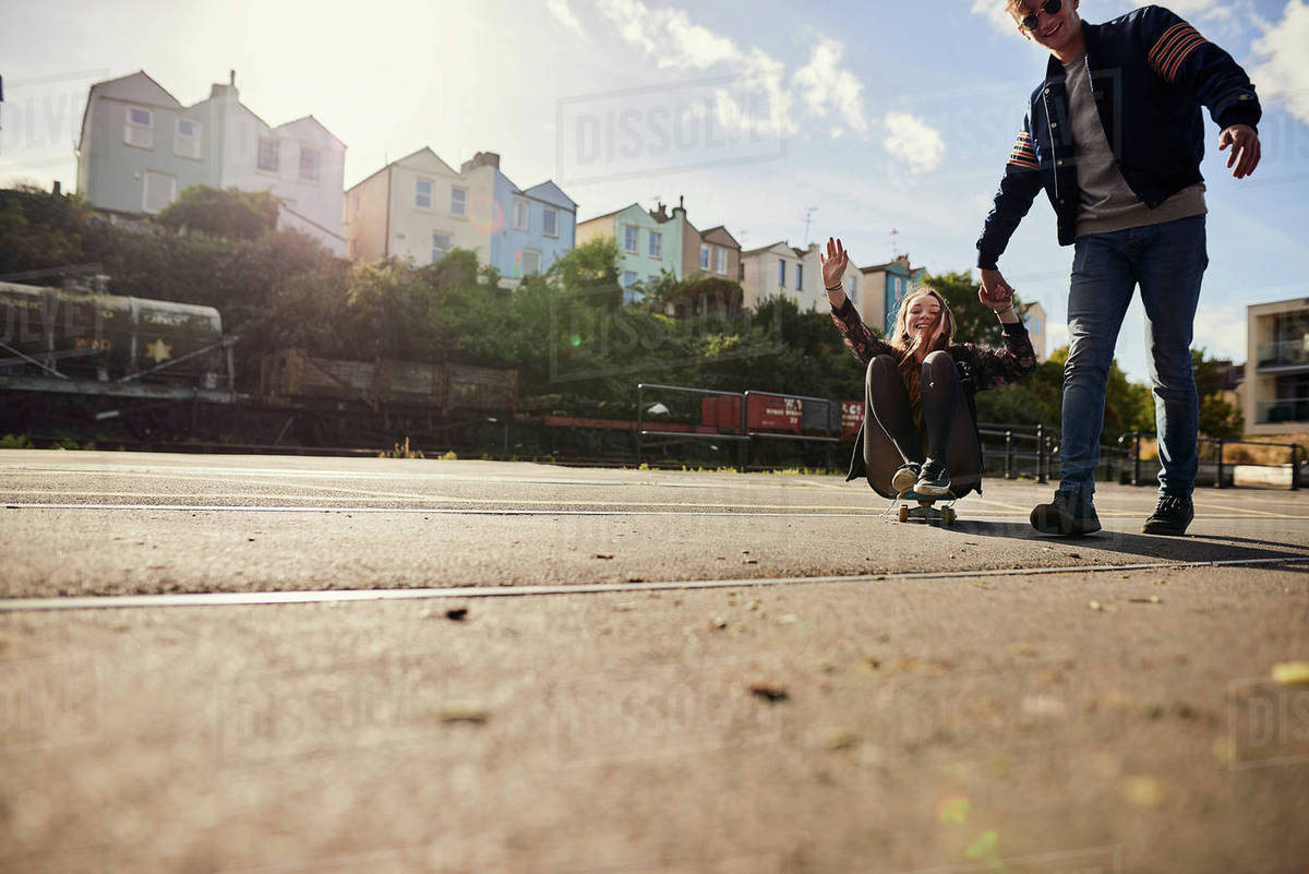 Two friends fooling around, young man pulling young woman along on ...