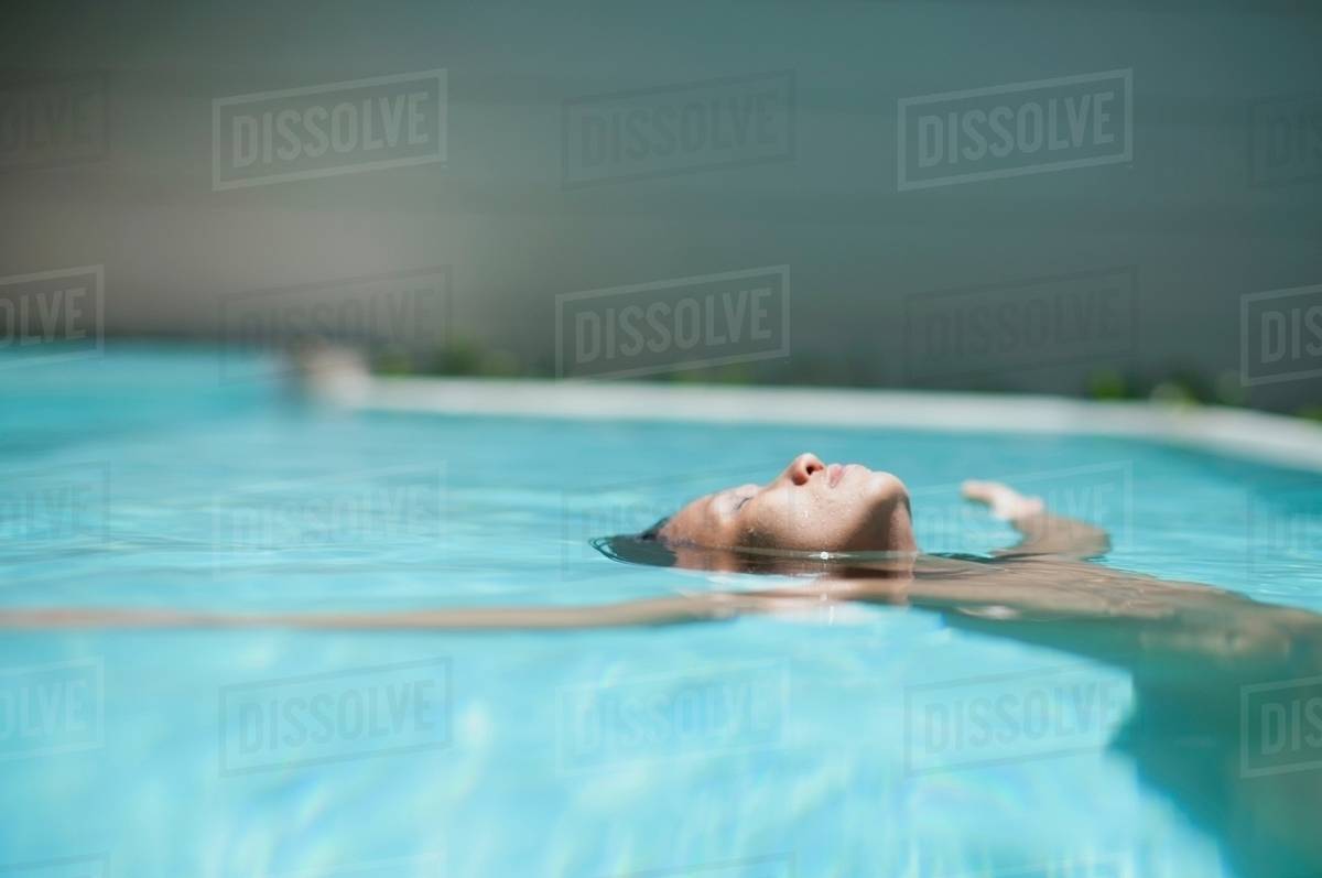 Woman floating in swimming pool - Stock Photo - Dissolve