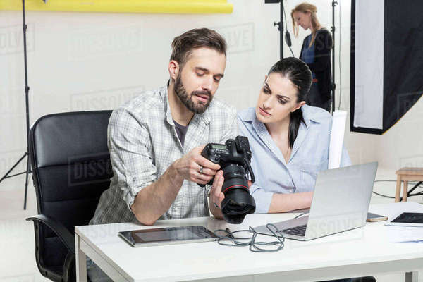 Stylist and photographer reviewing shoot on digital SLR in photography ...