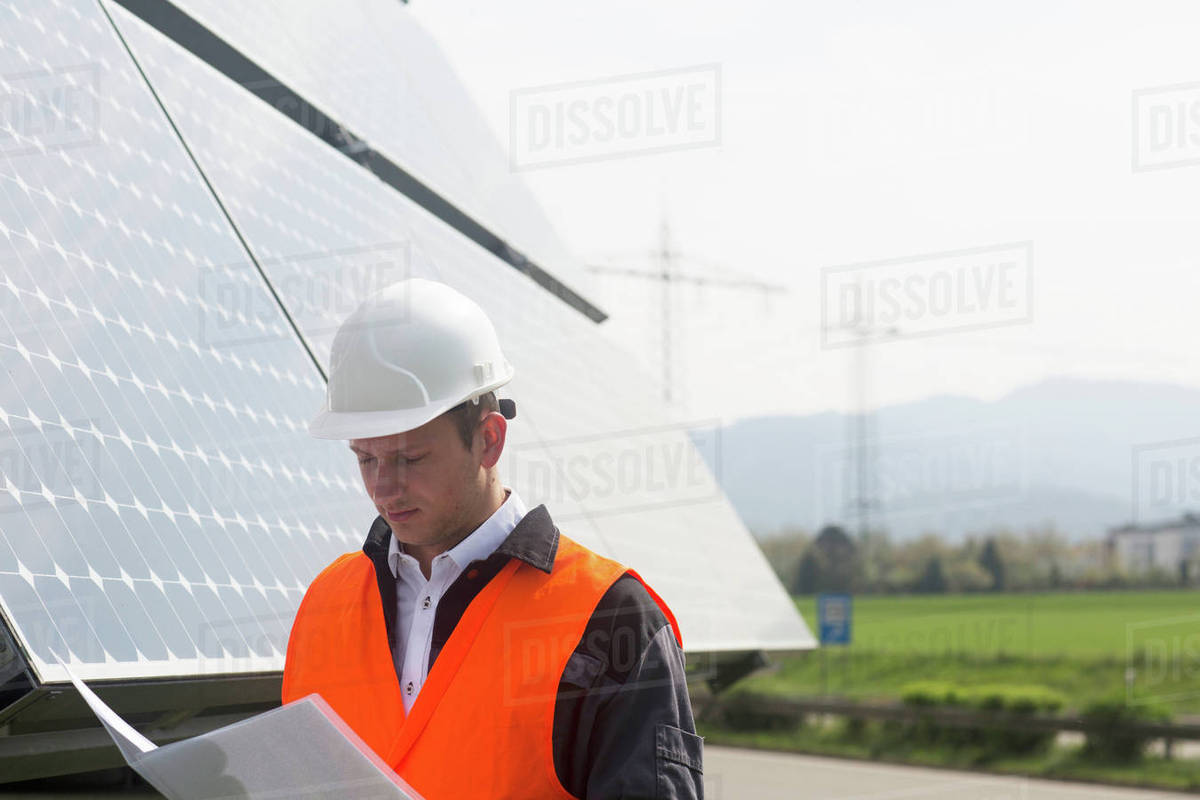 Male engineer looking at paperwork on solar panel site - Stock Photo ...