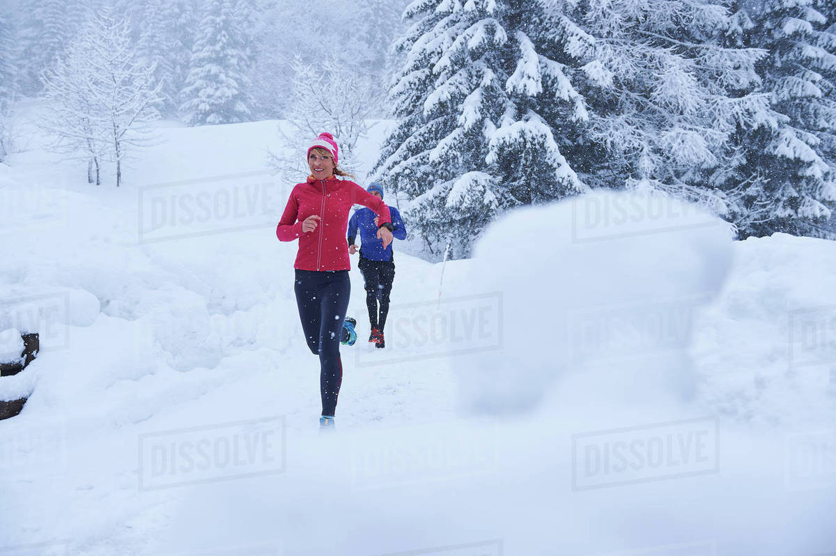Female and male runners running on track in deep snow, Gstaad ...