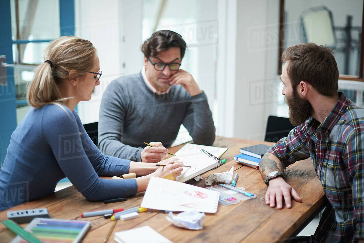 Design team having brainstorming meeting at design studio desk ...