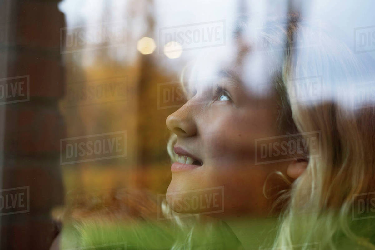 Girl with long blond hair looking up through window - Stock Photo ...