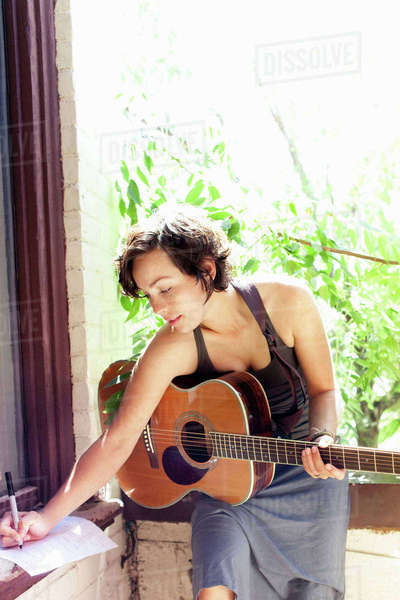Woman writing music with guitar - Stock Photo - Dissolve