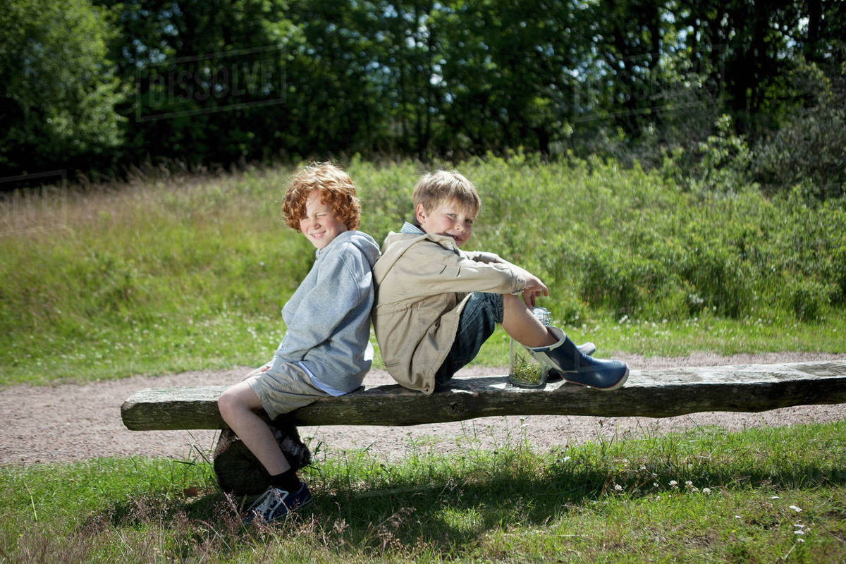 Children sitting on wooden bench - Stock Photo - Dissolve