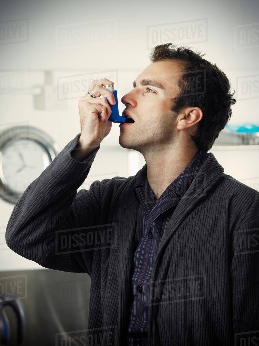 Man using asthma inhaler - Stock Photo - Dissolve