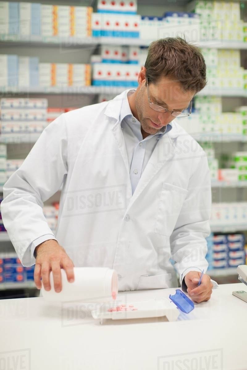 Pharmacist counting pills at counter - Royalty-free Stock Photo | Dissolve