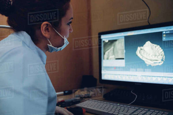 Female dentist looking at model of teeth on computer screen - Stock ...