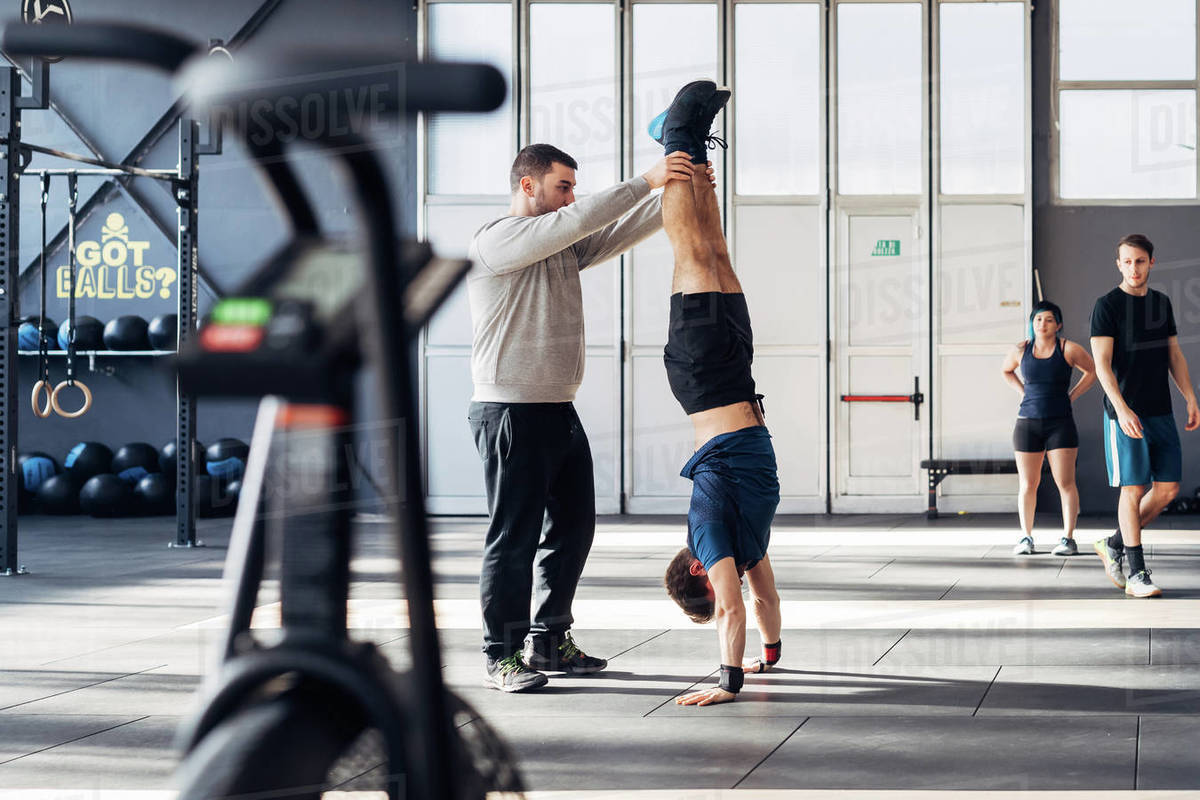 Man in gym helping friend do handstand - Royalty-free Stock Photo ...