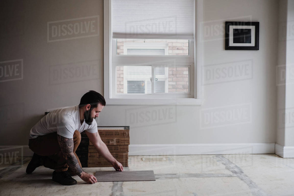 Man installing floor tiles - Royalty-free Stock Photo | Dissolve